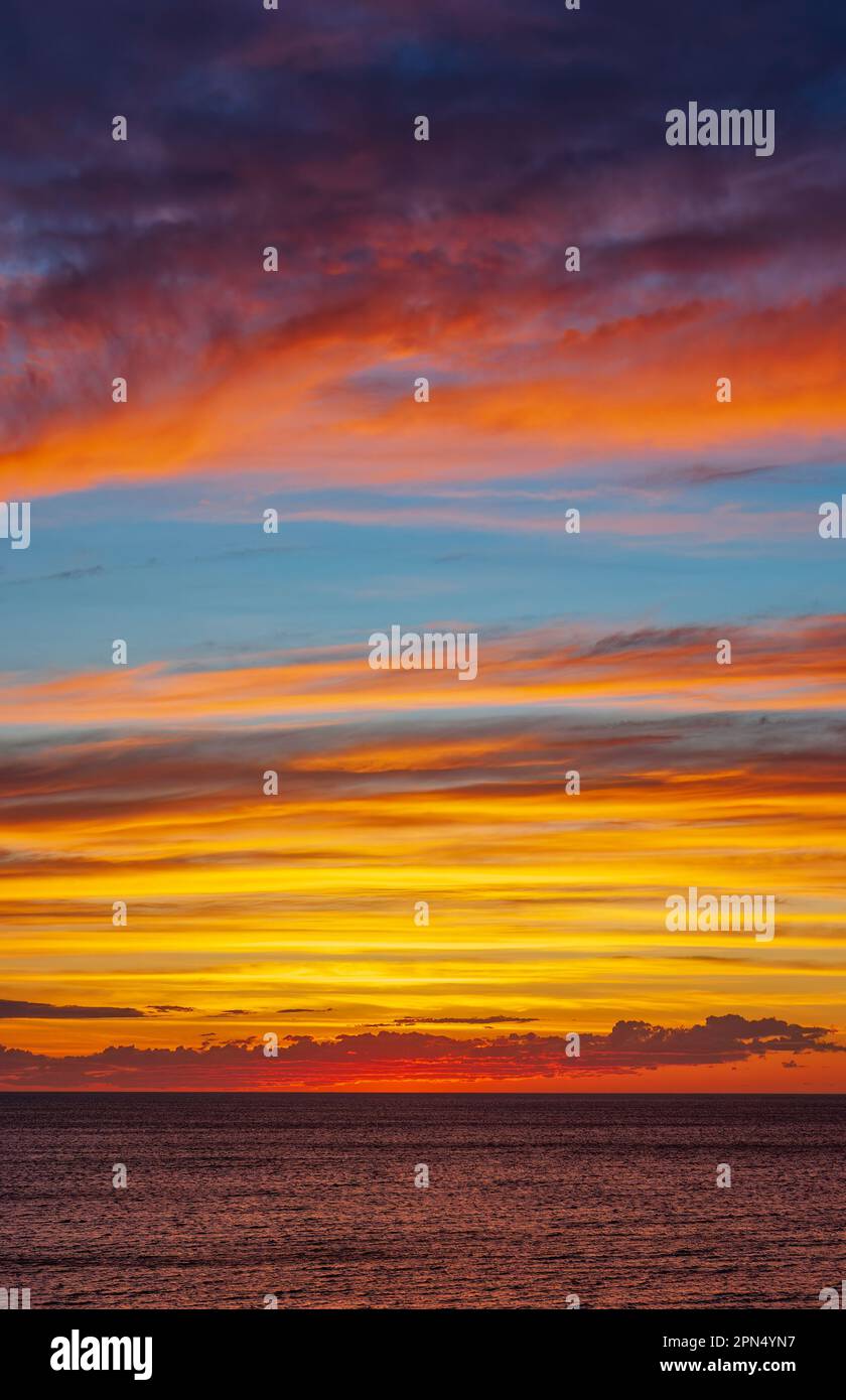Colorful sunset above rippled waters. Dramatic sky in red and orange ...