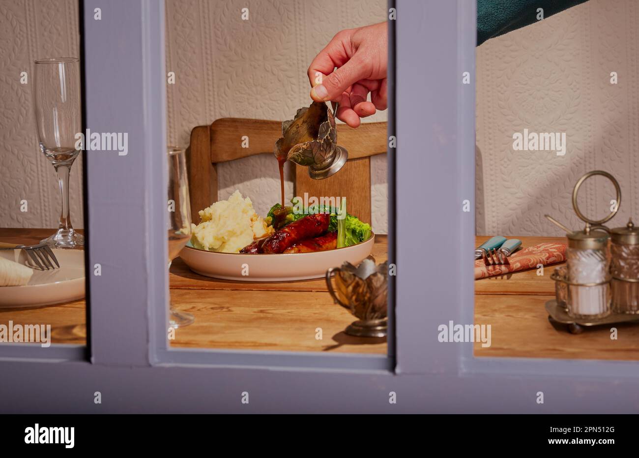 View threw a window of a cooked dinner with gravy being poured on to it ...