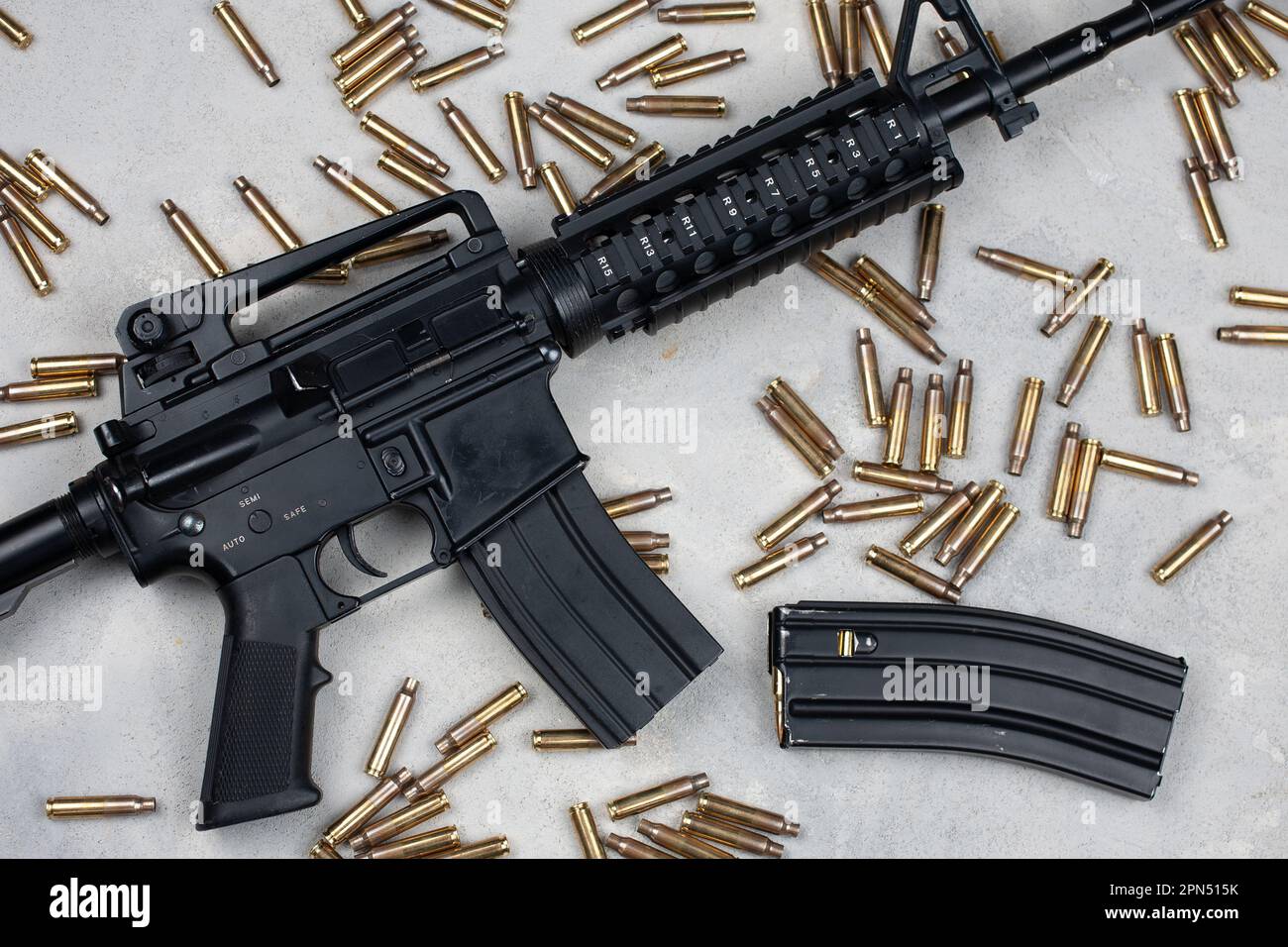 M4 carbine and 5.56mm shells and magazine with bullets on grey concrete ...