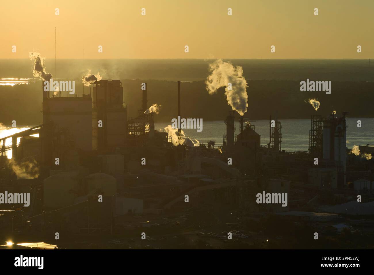 Large factory structure with smoke from production process rising up ...