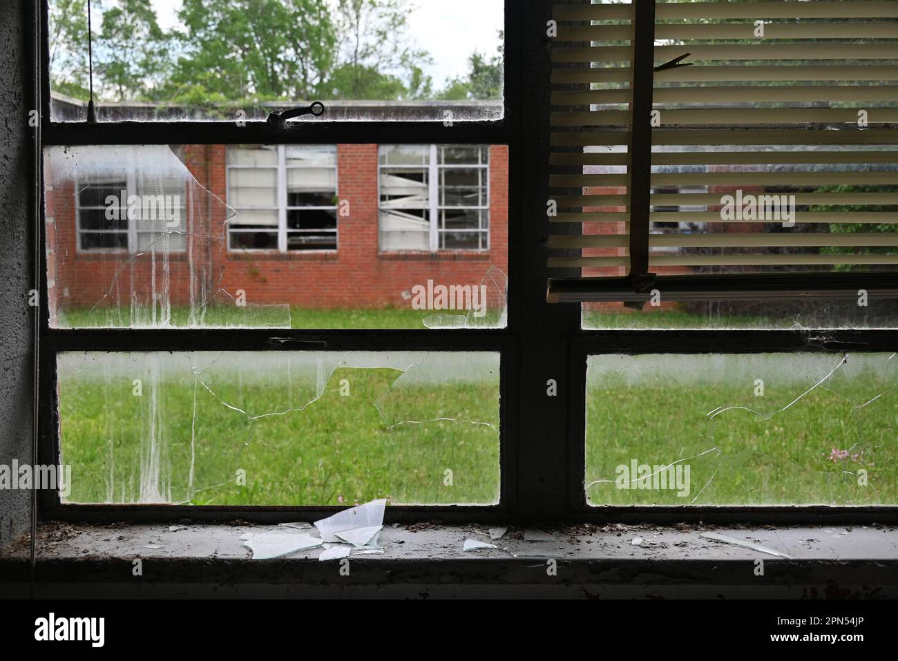 Looking out a broken classroom window into the courtyard of a school ...