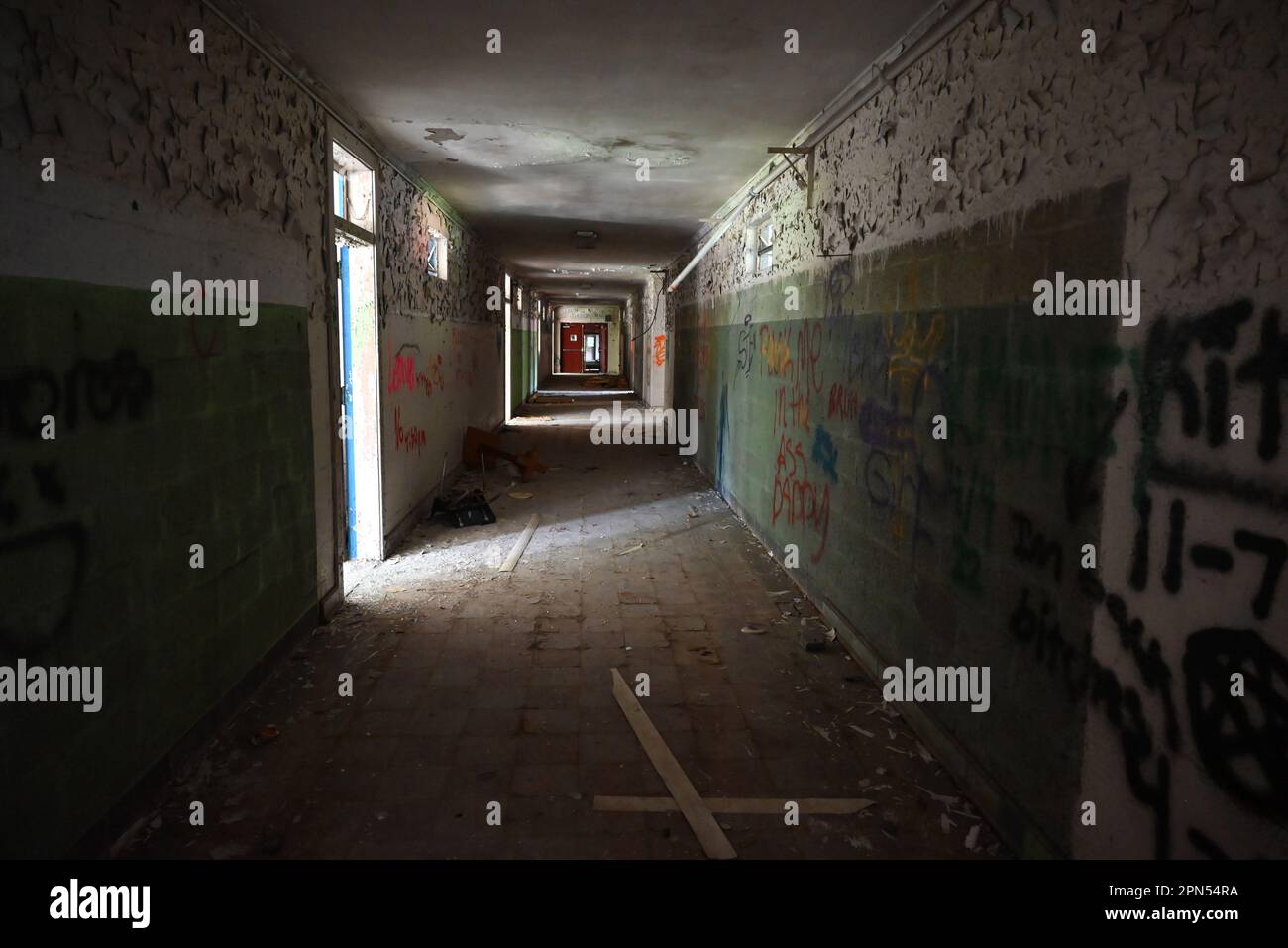 A dark hallway filled with graffiti and pealing paint in a school ...