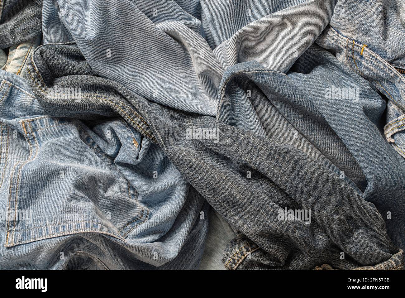 Lots of crumpled jeans pants, close up. Denim background. The concept ...