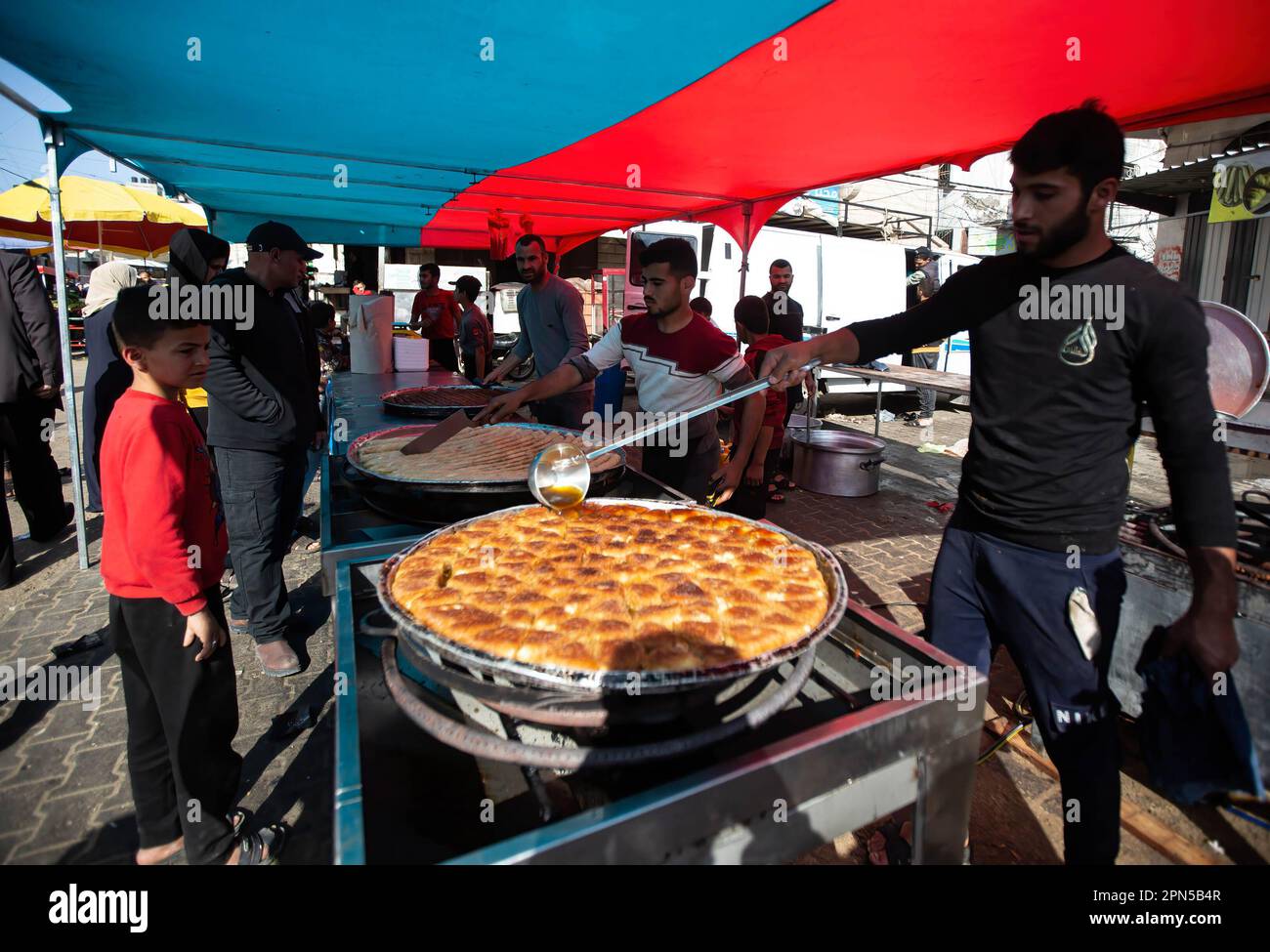 A Palestinian street vendor sells traditional sweets in a market during ...