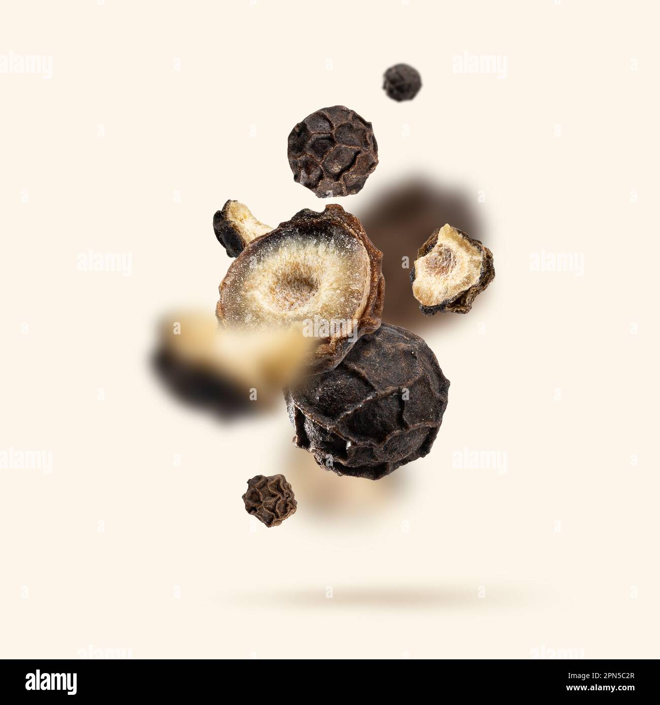 Close-up organic peppercorn, whole and sliced, flying on beige ...