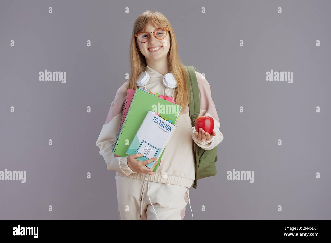 happy modern teenage girl in beige tracksuit with apple, backpack ...