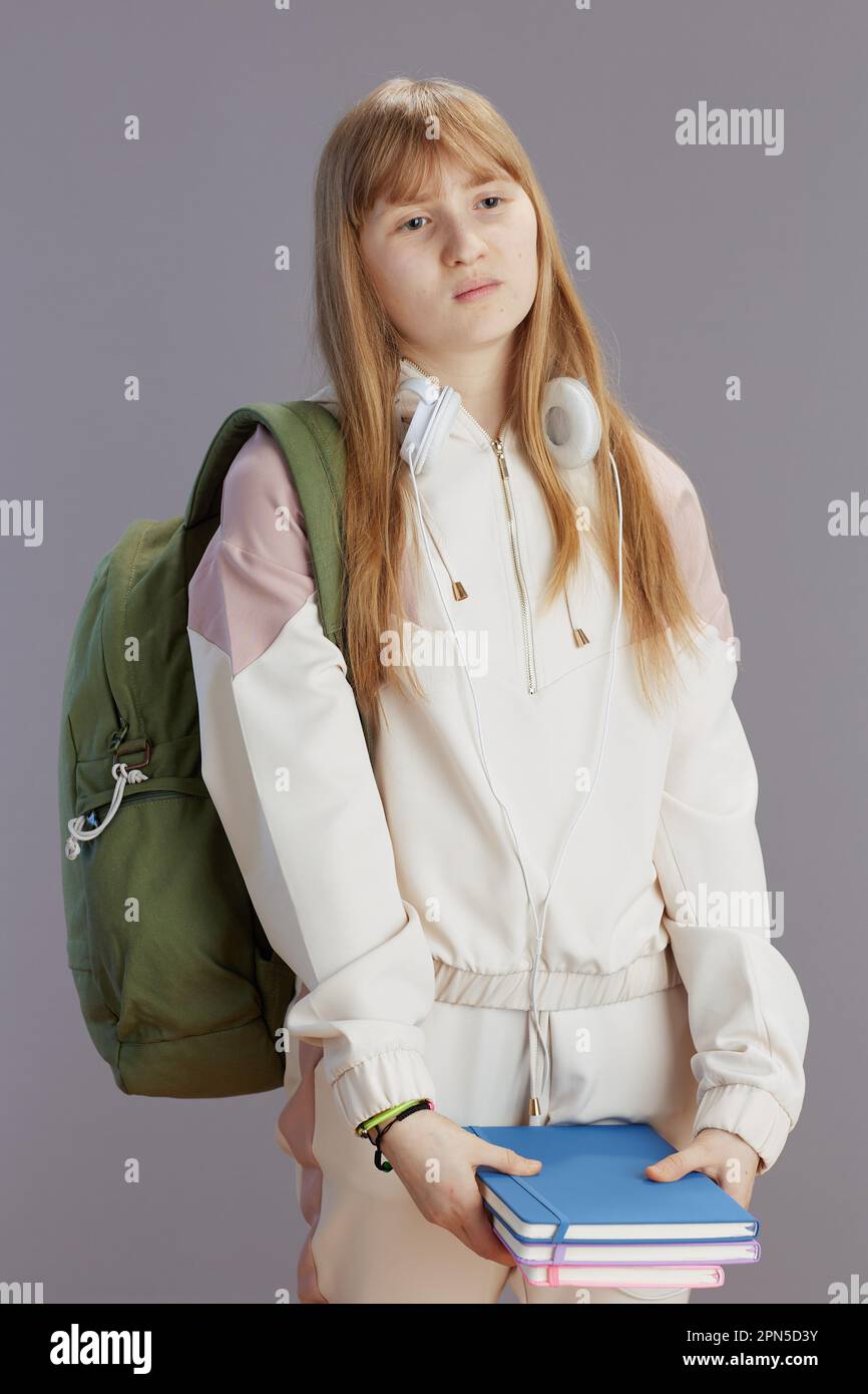 sad modern teenager girl in beige tracksuit with backpack, workbooks ...