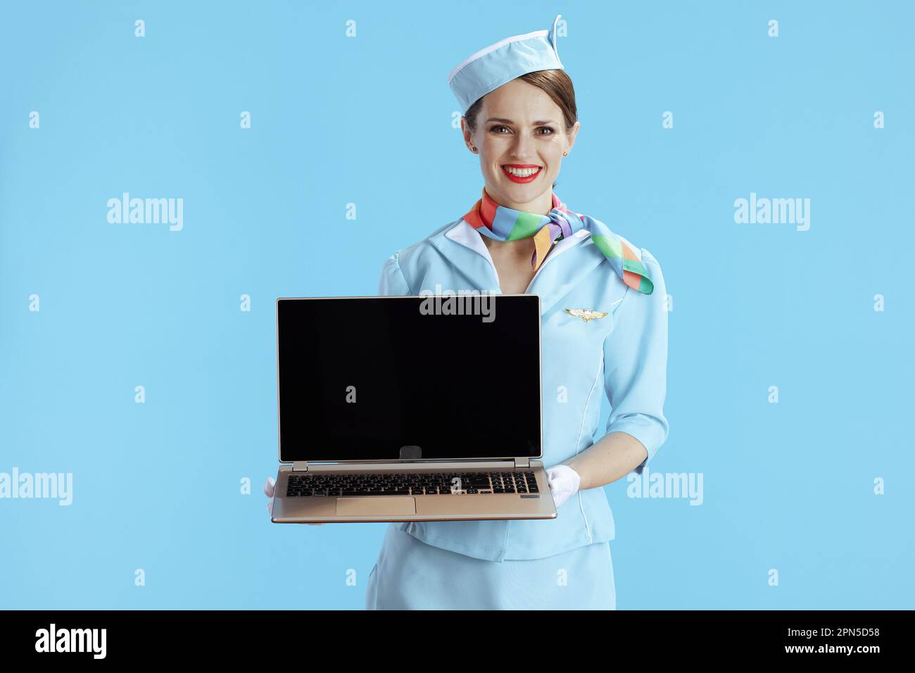 smiling elegant female flight attendant against blue background in blue ...