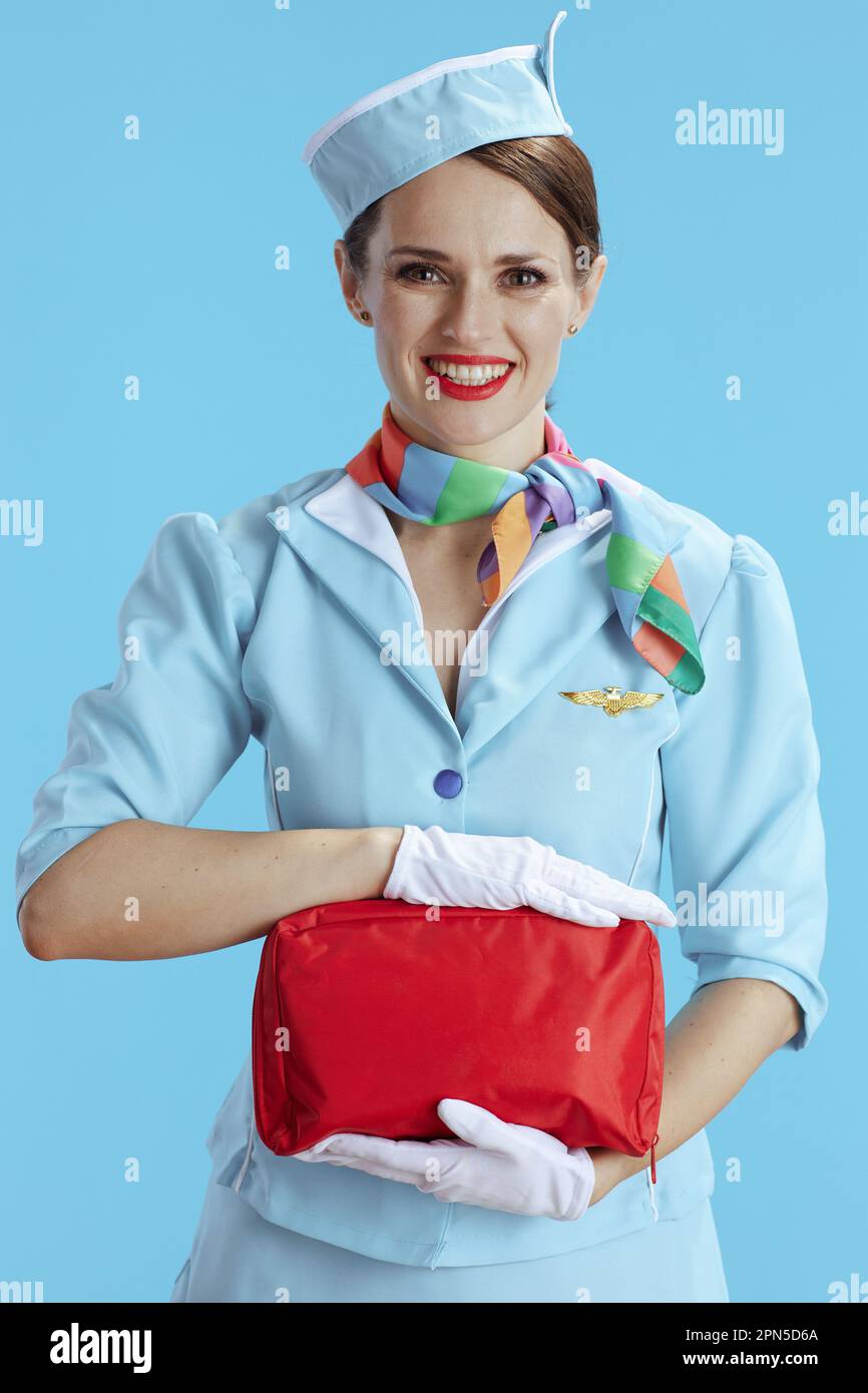 smiling elegant female flight attendant against blue background in blue ...
