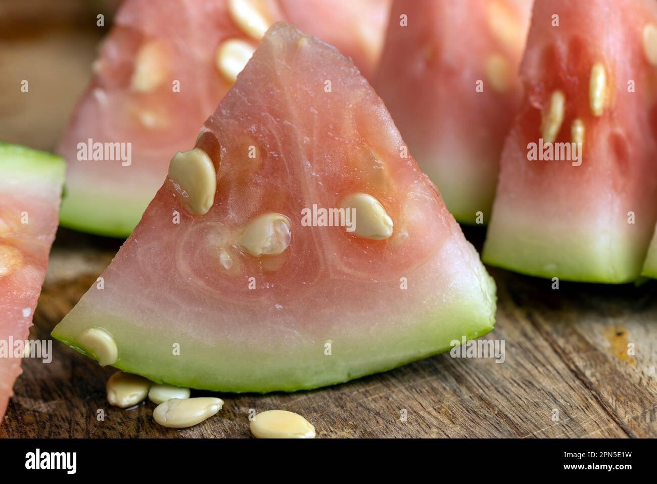 Unripe watermelon of small size with large white seeds and light pink ...