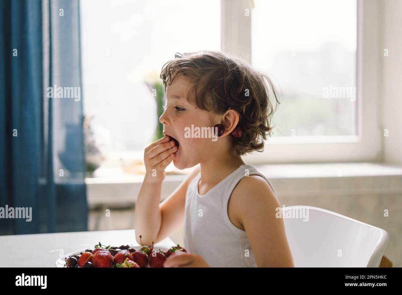 Cute beautiful little boy eating fresh cherry and strawberry Stock ...