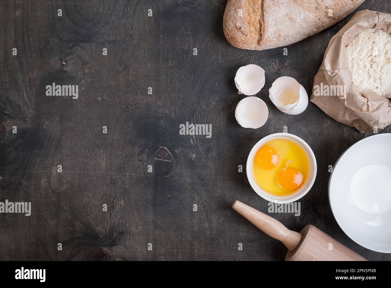Baking dark background with blank cook book, eggshell, bread, flour ...