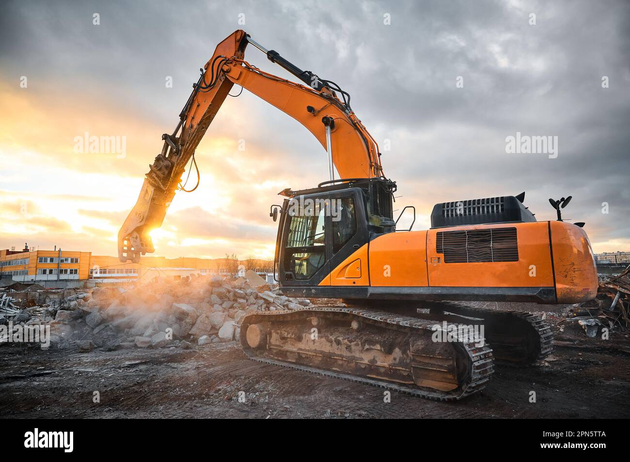 Excavator with concrete crusher at demolition site Stock Photo - Alamy