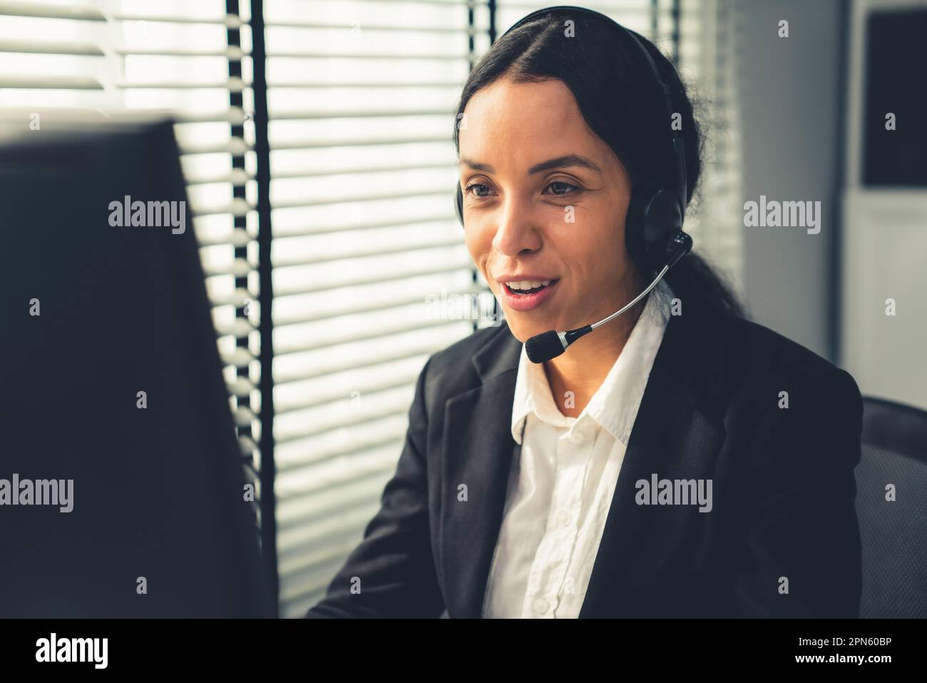 Competent female operator working on computer and talking with clients. Concept relevant to both ...