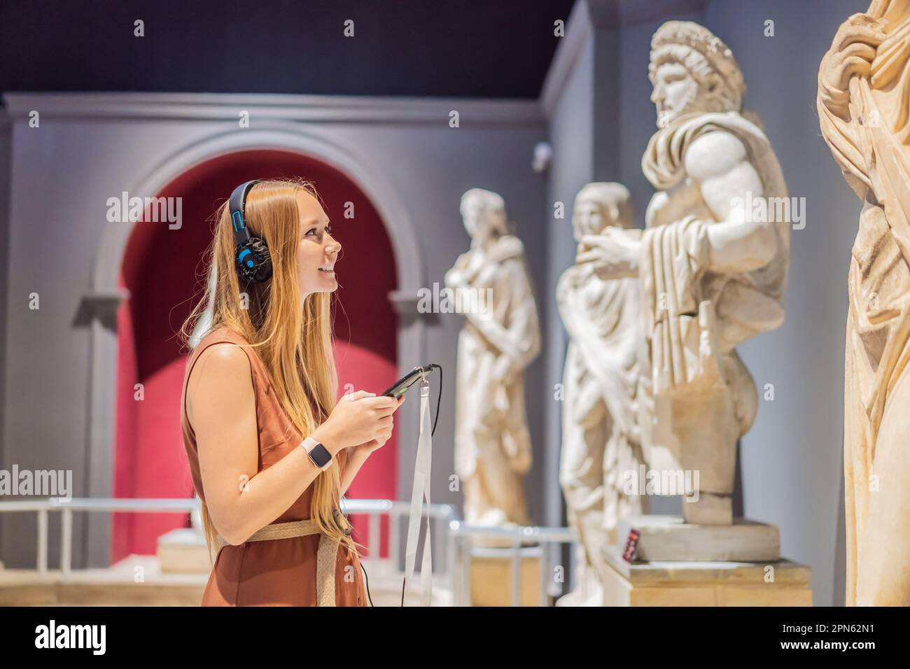 Portrait of contemporary young woman looking at sculptures and ...