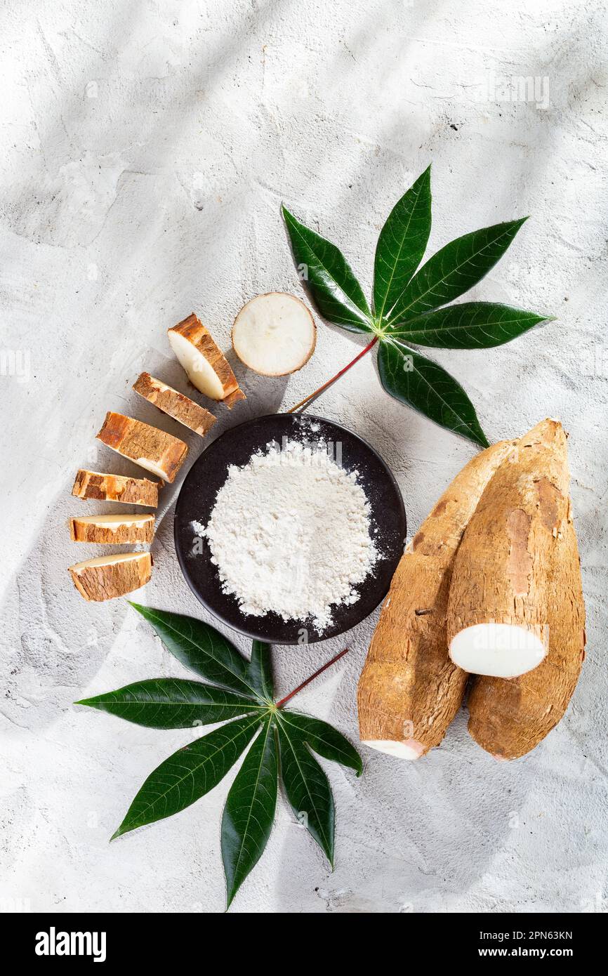 pile of cassava root and cassava flour on a gray and white textured ...