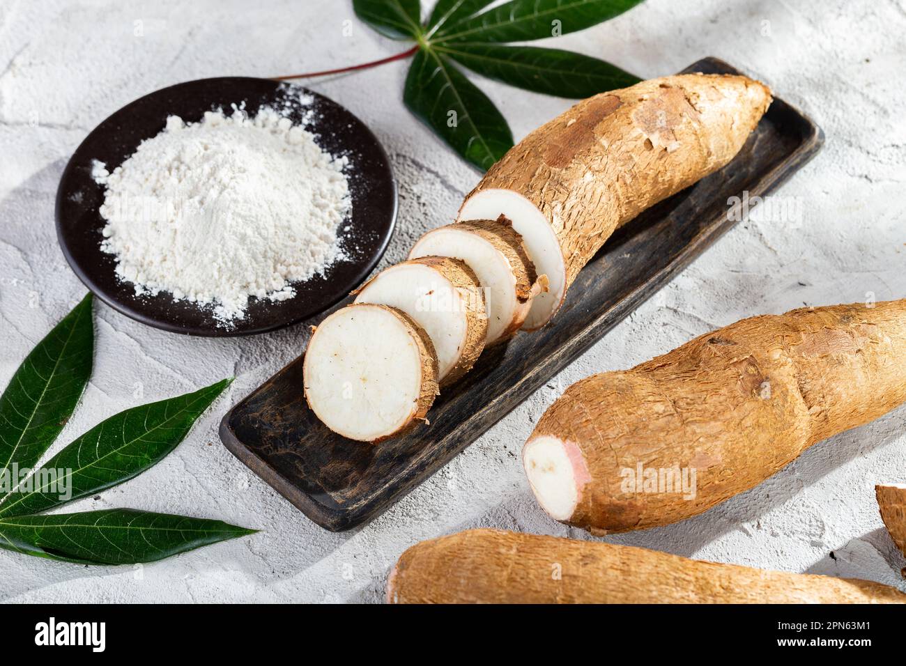 pile of cassava root and cassava flour on a gray and white textured ...