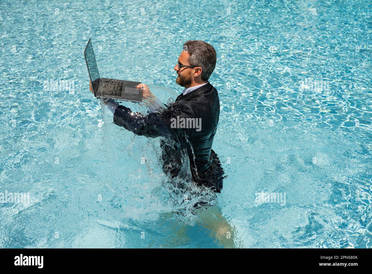 Business man in suit working on laptop in swimming pool. Travel tourism ...