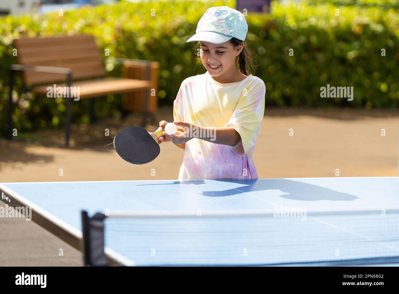 Young teenager girl playing ping pong. She holds a ball and a racket in ...