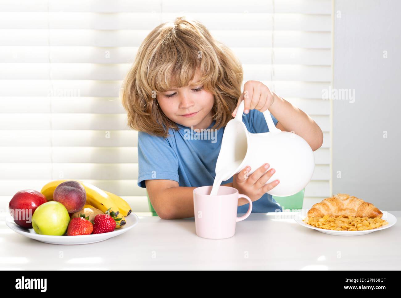 Kid pouring whole cows milk. Little child boy having healthy breakfast ...