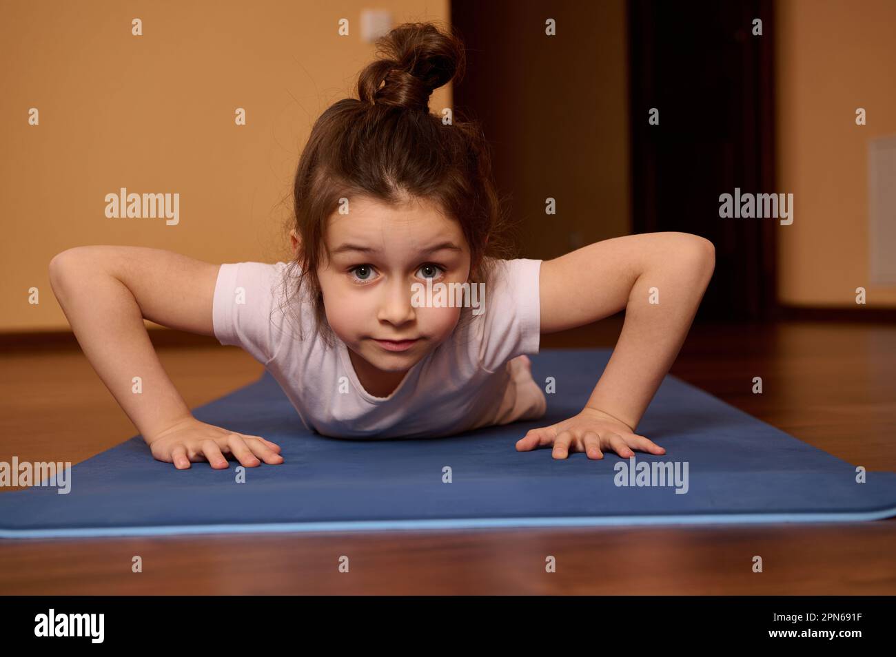 Close-up front view of adorable active little girl doing push ups on a ...
