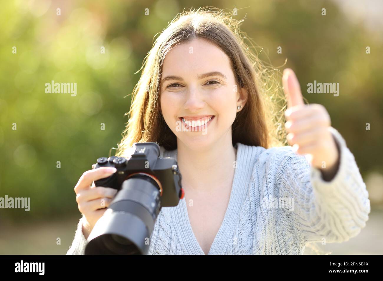 Front view portrait of a happy photographer holding mirrorless camera ...