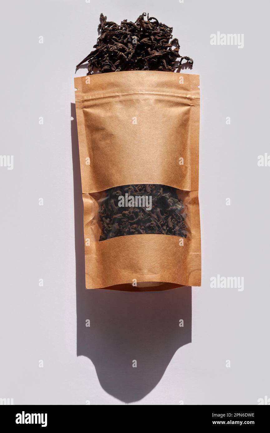 Brown kraft paper pouch bags with black tea leaves top view with harsh ...