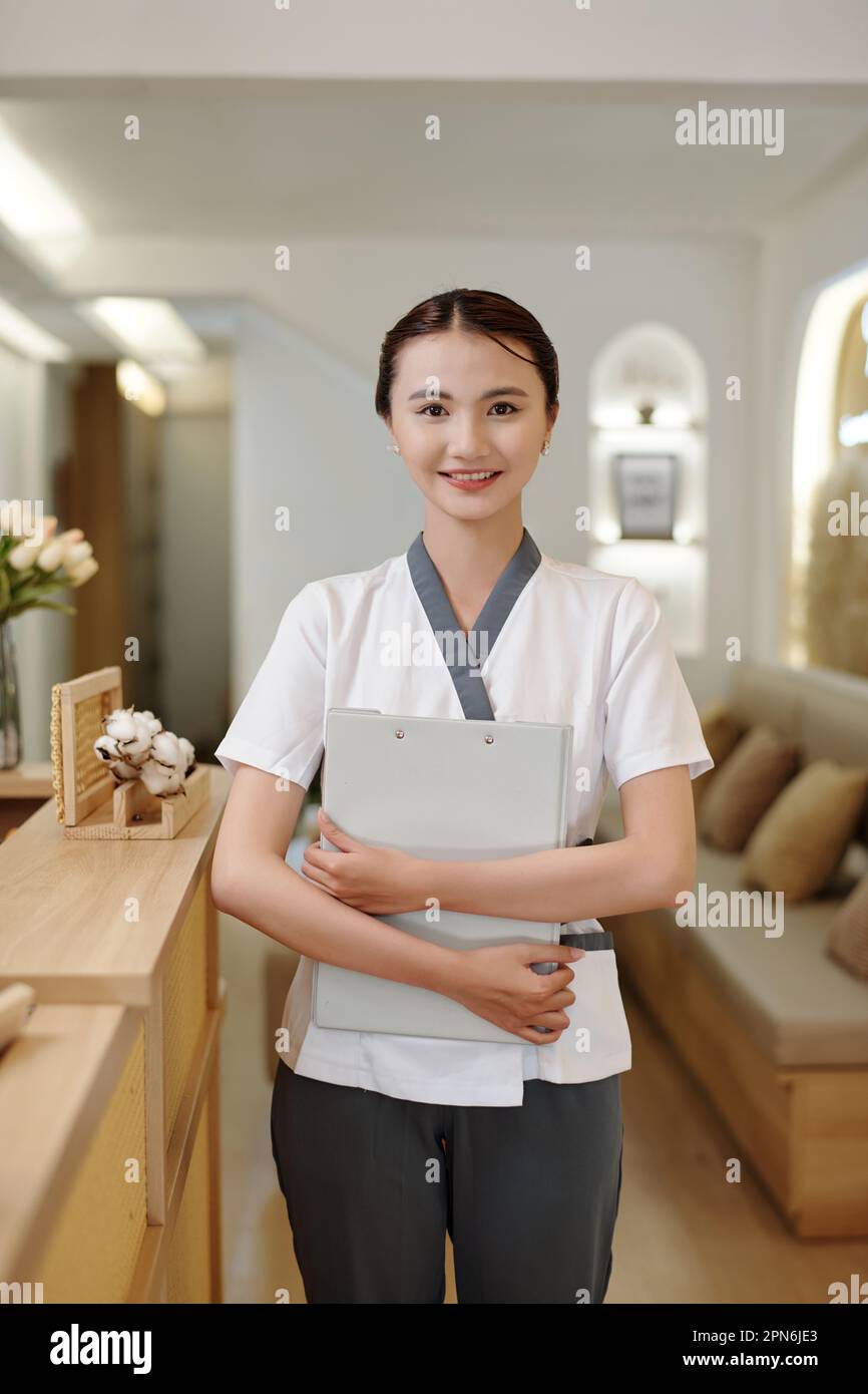 Portrait of positive beauty salon receptionist holding documents folder ...