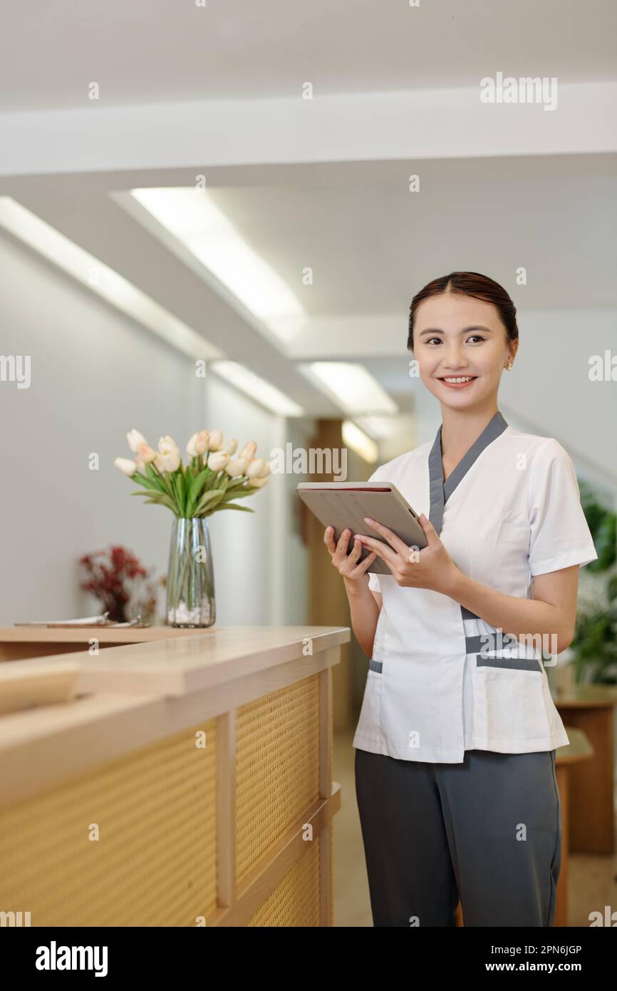 Joyful spa salon receptionist checking schedule on tablet computer ...