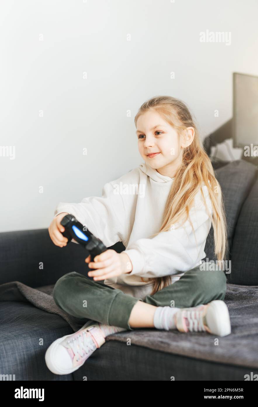 A little girl holding game controller playing video games Stock Photo ...