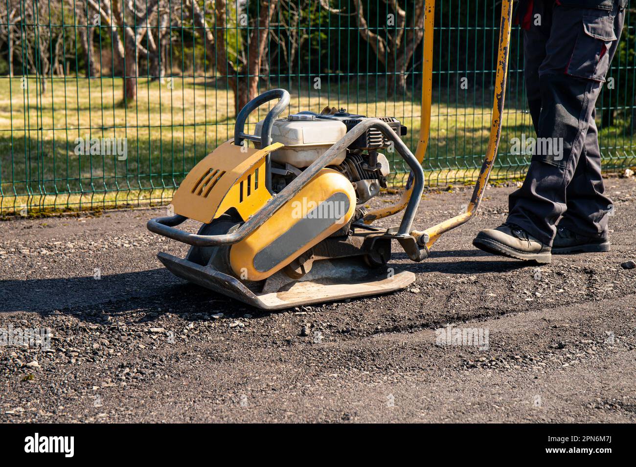 Close up view of home owner use plate compactor tool to build parking ...