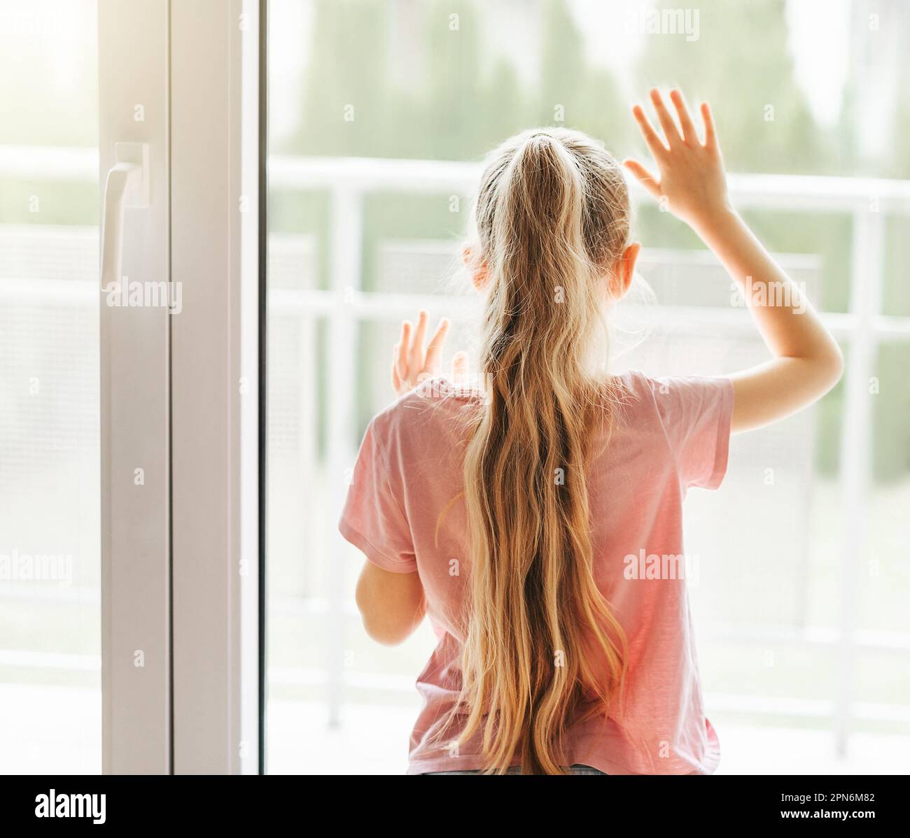 Lonely little girl looking out window, standing at home alone Stock ...