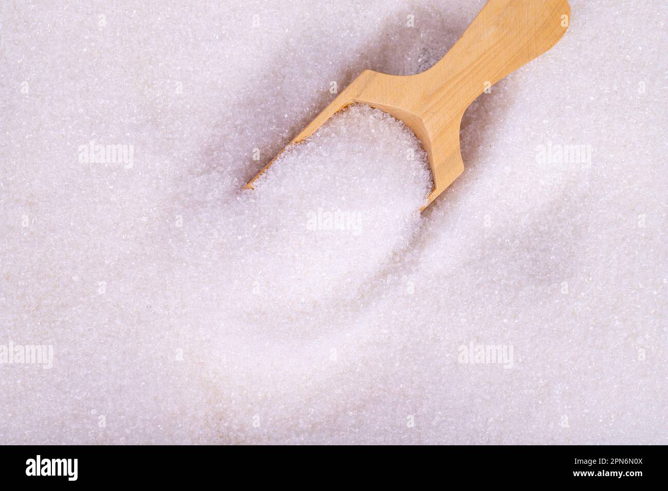 White granulated sugar. Top view wooden spoon inside heap of white ...
