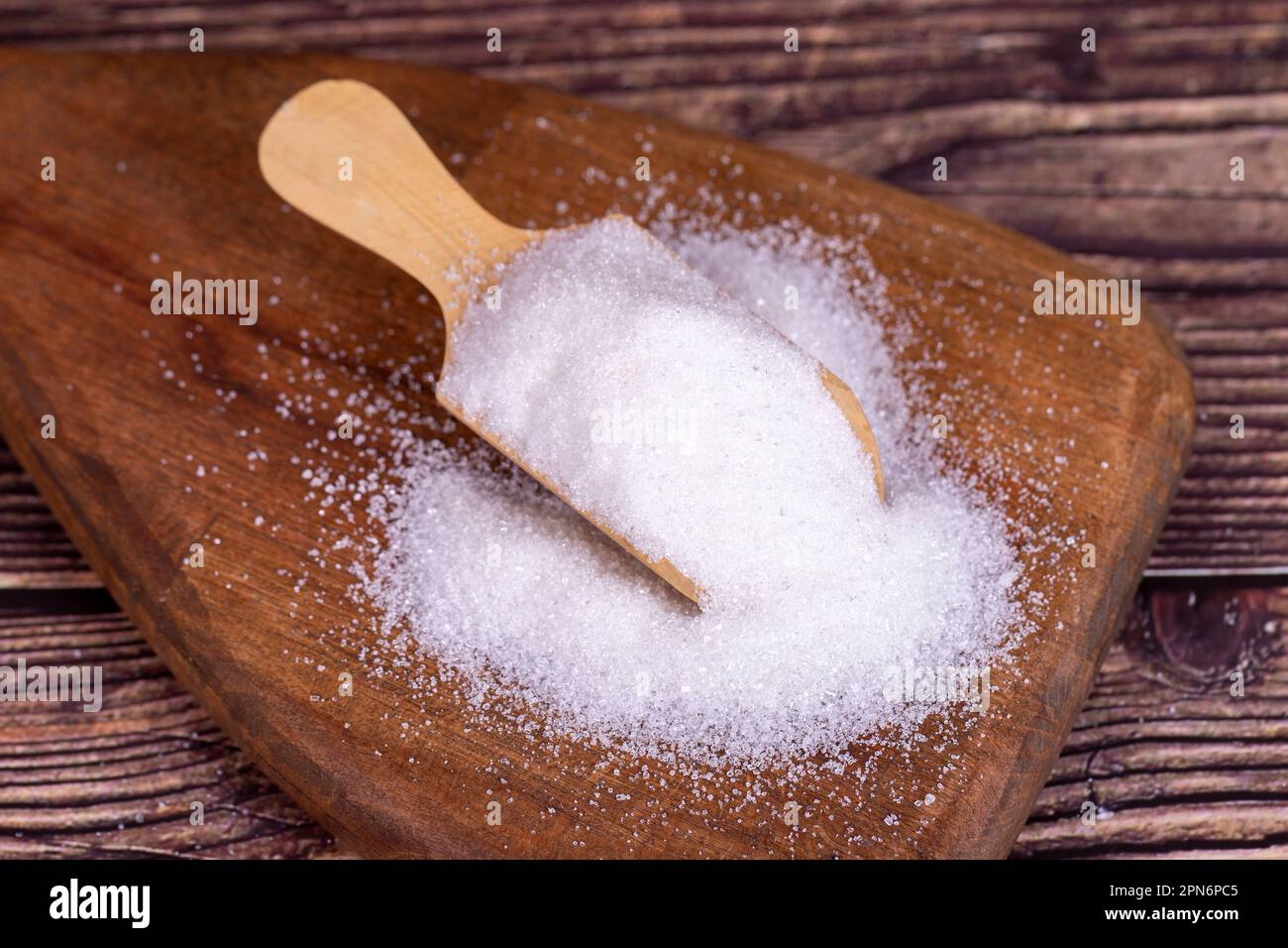 White refined sugar on wood background. Close-up of granulated sugar in ...
