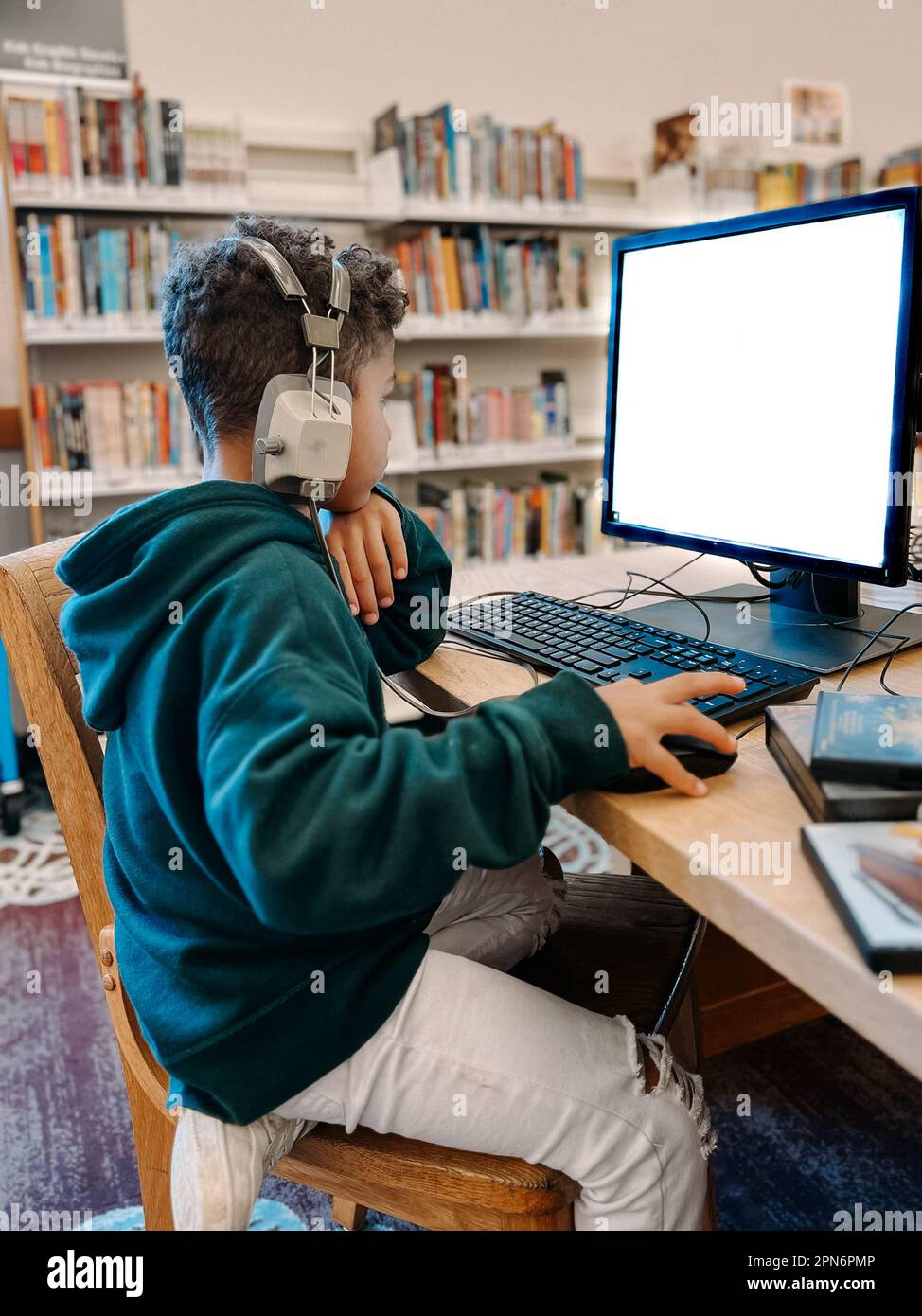 Young boy with headphones using computer at public library Stock Photo ...