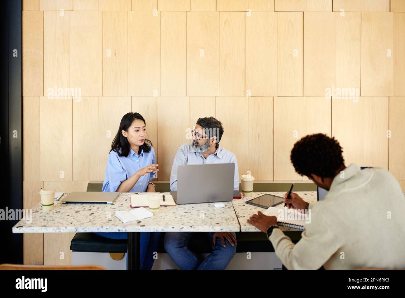 businesswoman explaining coworker over laptop sitting in coffee shop ...