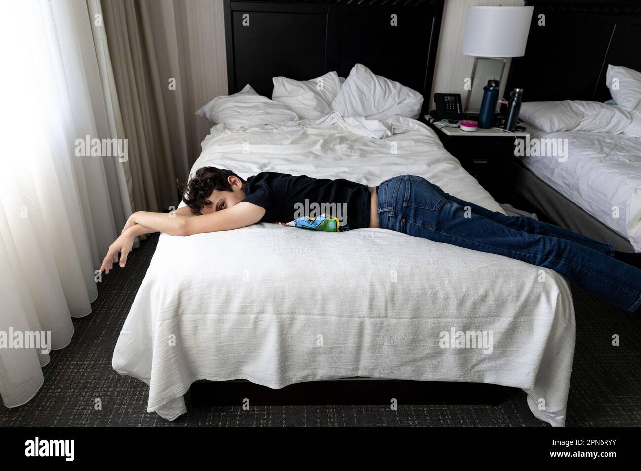 Teen Boy Lays Across Bed In hotel Room Stock Photo - Alamy