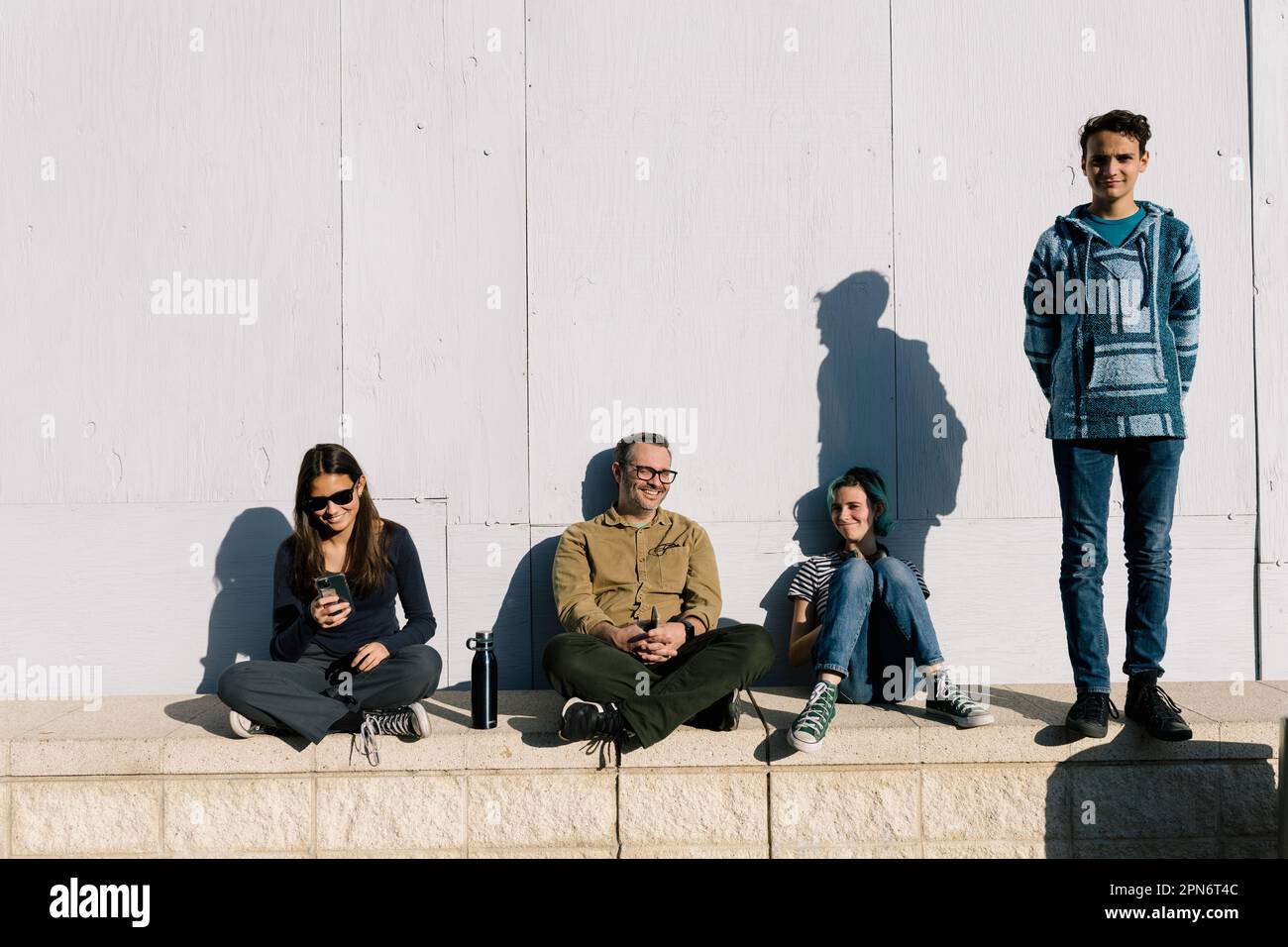 Happy Father And Kids Hanging Out On A wall In The Sun Stock Photo - Alamy