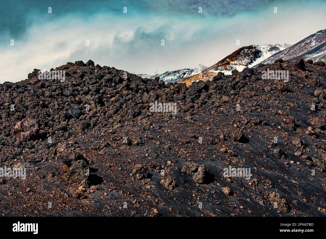 Lapilli and black earth, the snowy slopes of Etna in the background. A ...