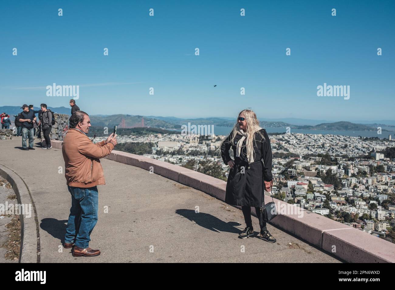 Tourists take photos from the Twin Peaks. San Francisco is renowned for ...