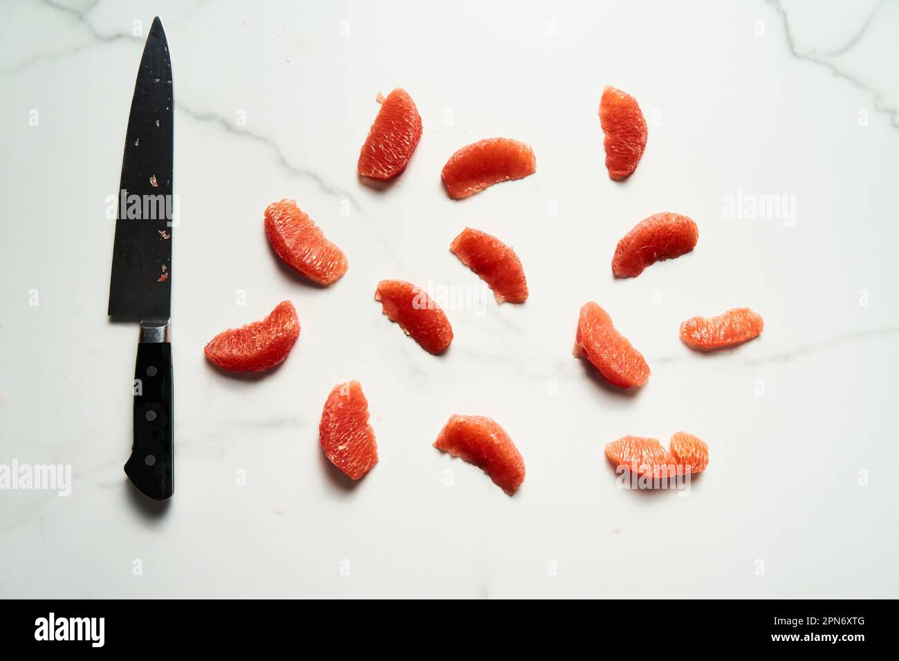 Peeled and sliced, divided in sections grapefruit with a knife next to ...