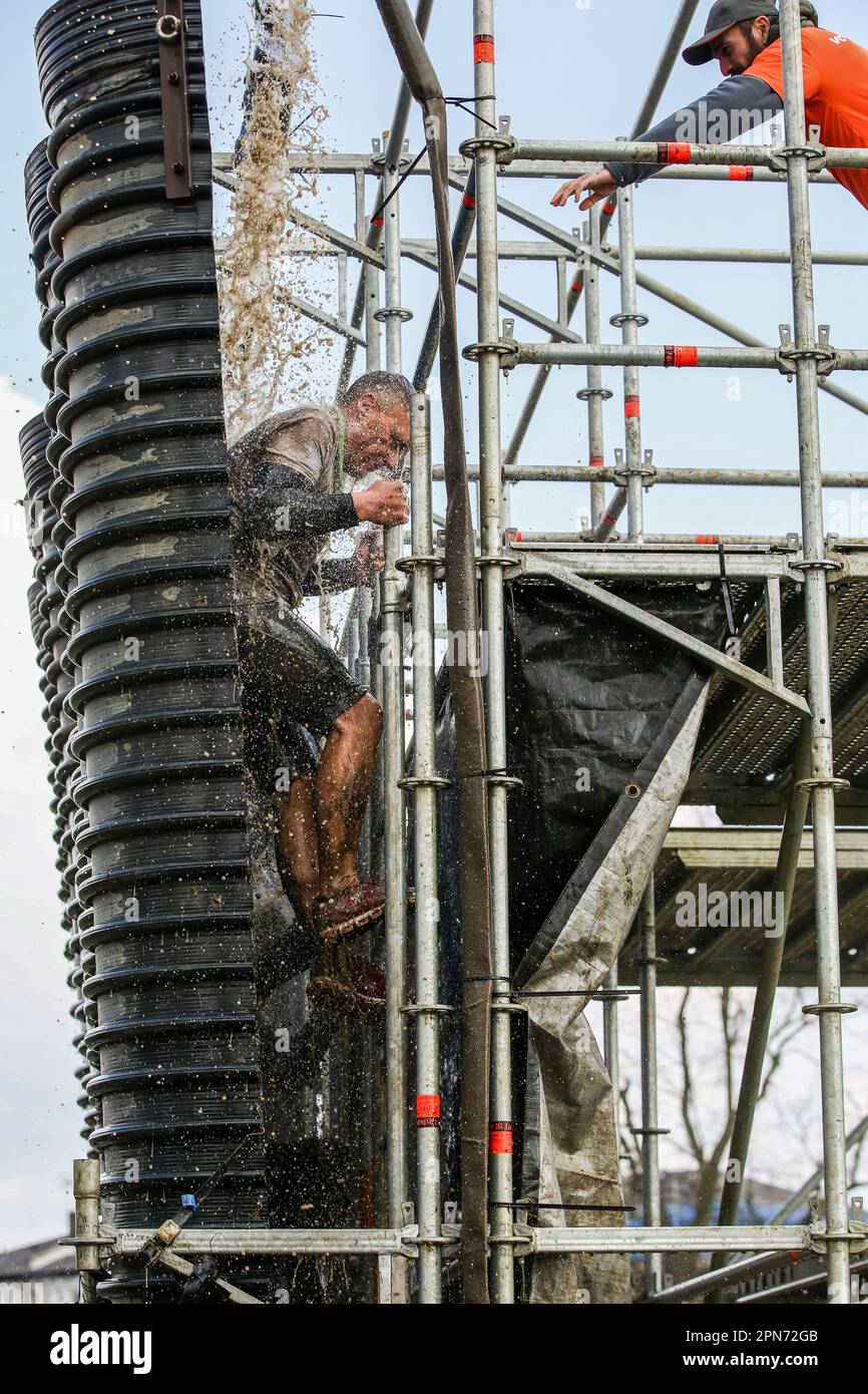 A participant climbs as water falls on him during the Tough Mudder race ...