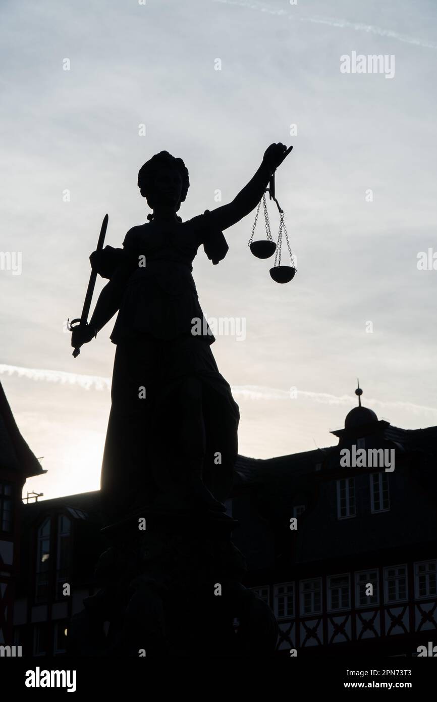 Backlit monument of Lady Justice with a blue sky in the background ...