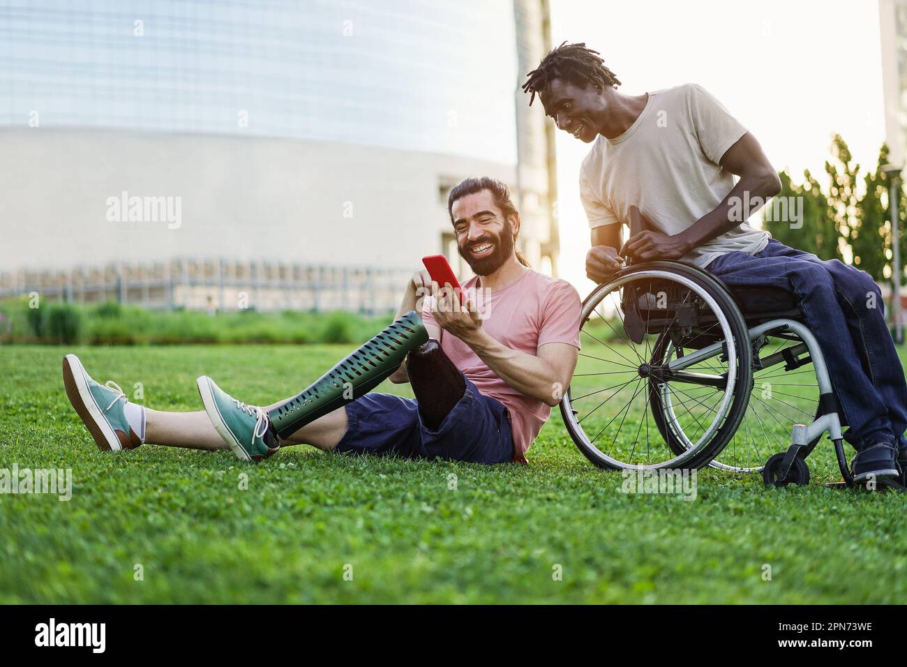 Multiracial friends with disability having fun using mobile phone at ...