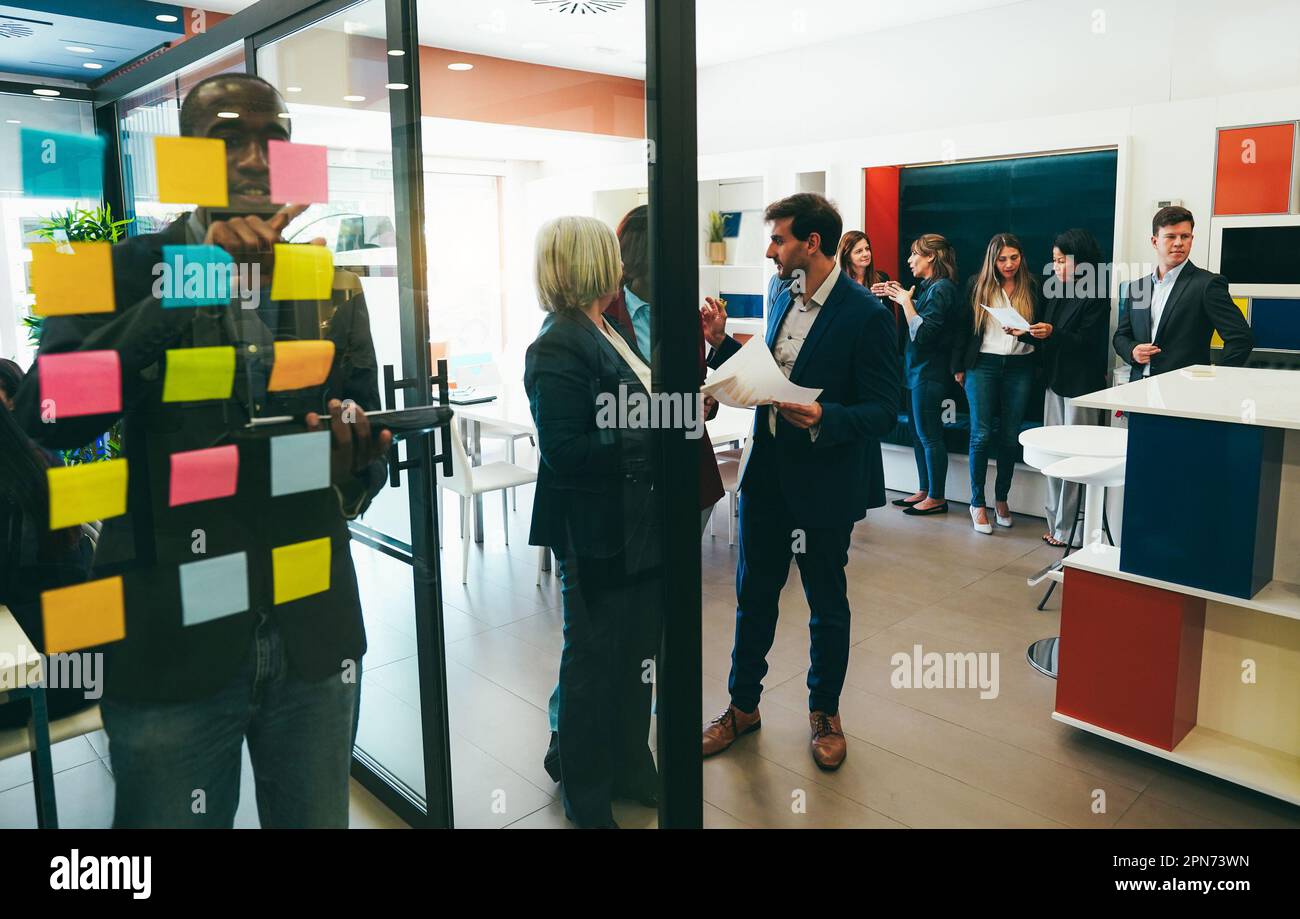 Multiracial colleagues working inside business office with glass walls ...