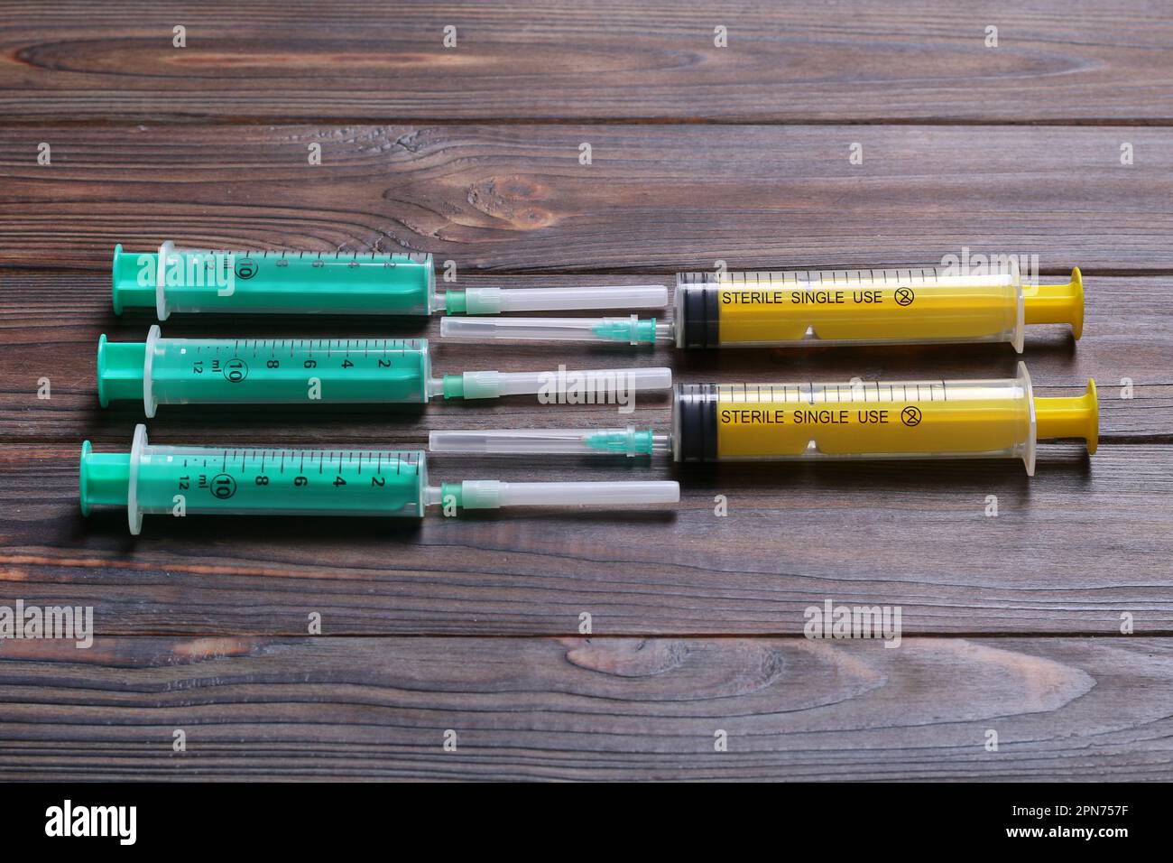 Top view of many syringes prepared for injection at wooden background ...