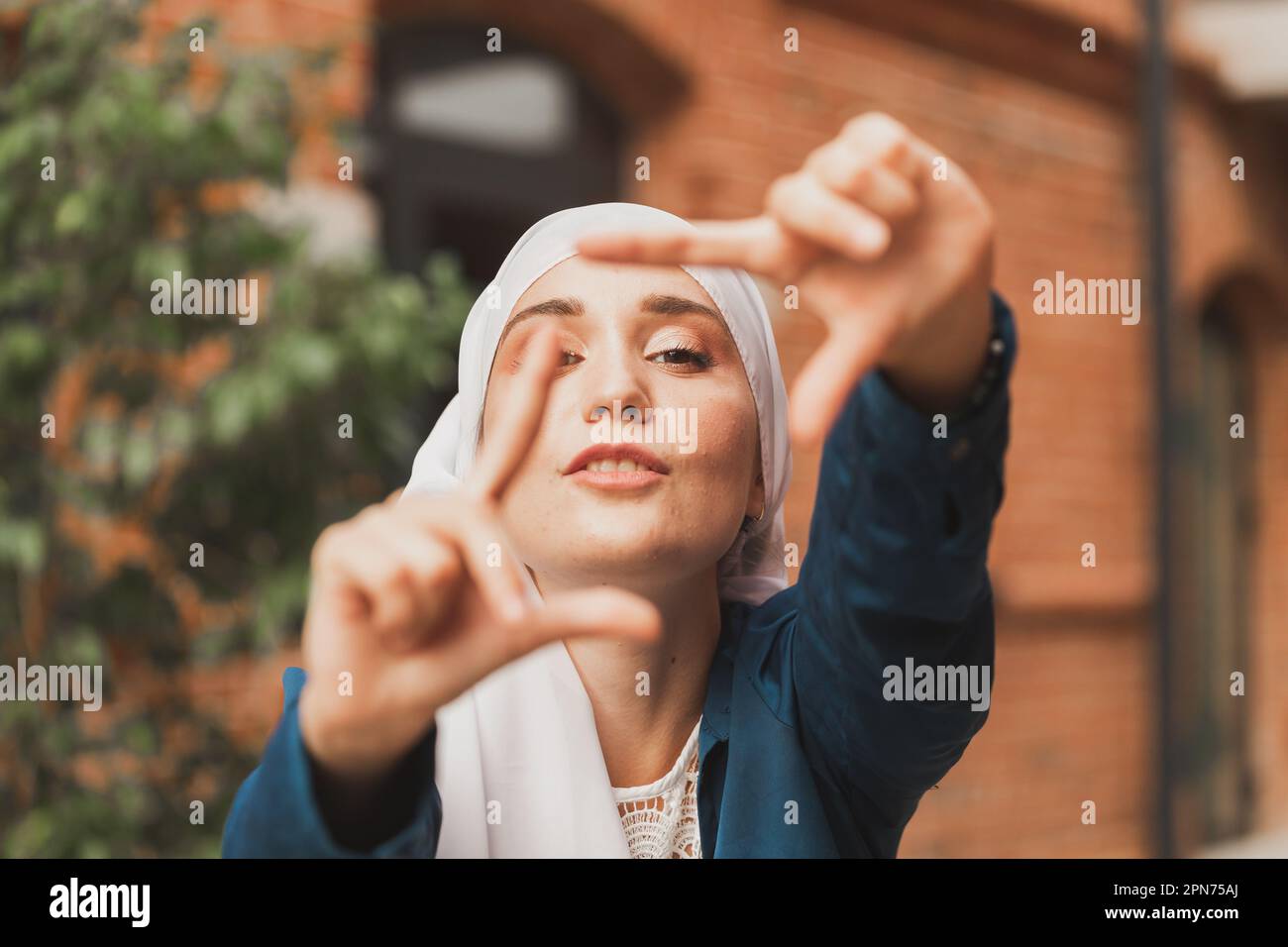 Portrait of young muslim girl making a camera frame with fingers ...