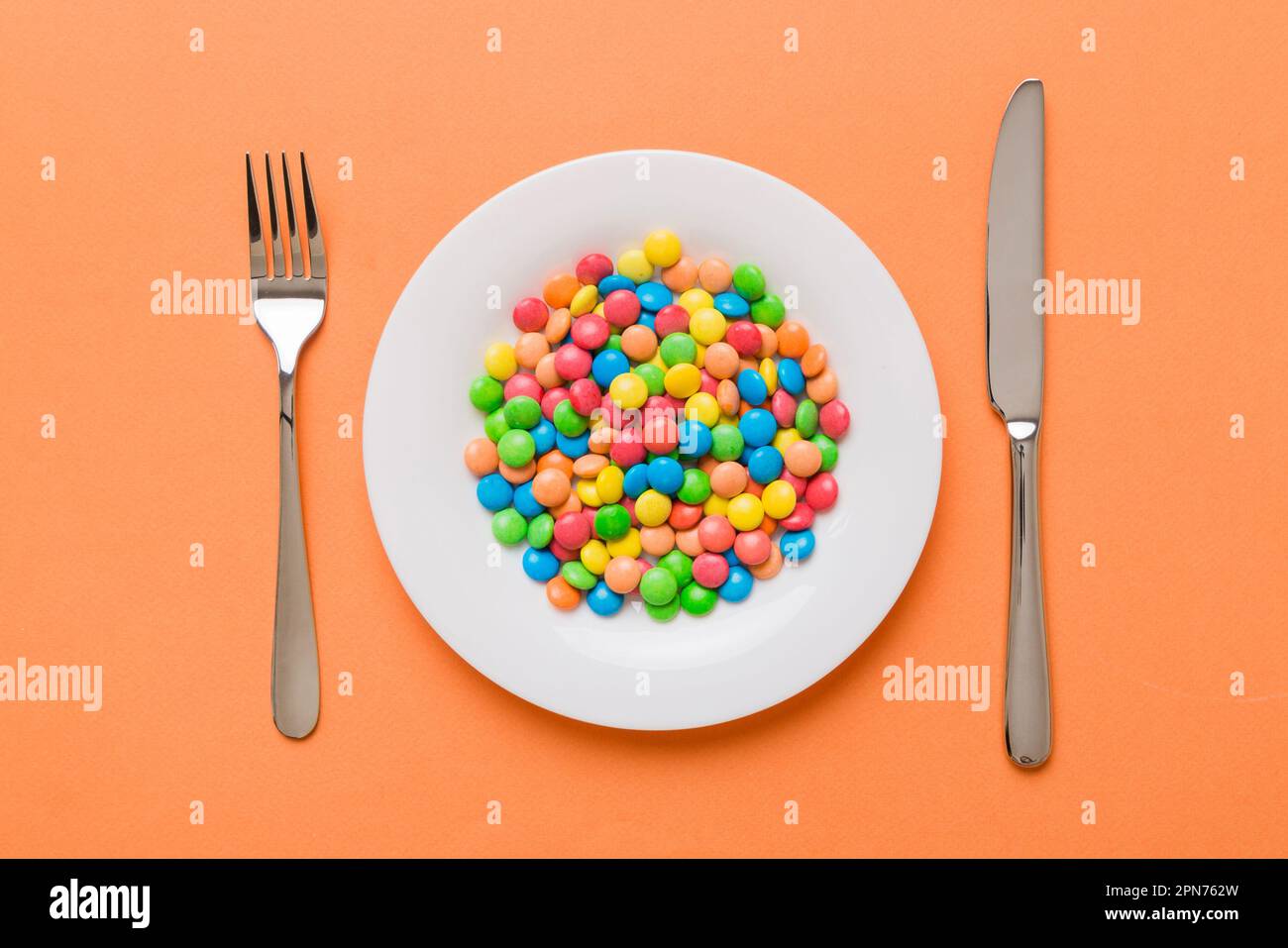 cutlery on table and sweet plate of candy. Health and obesity concept ...