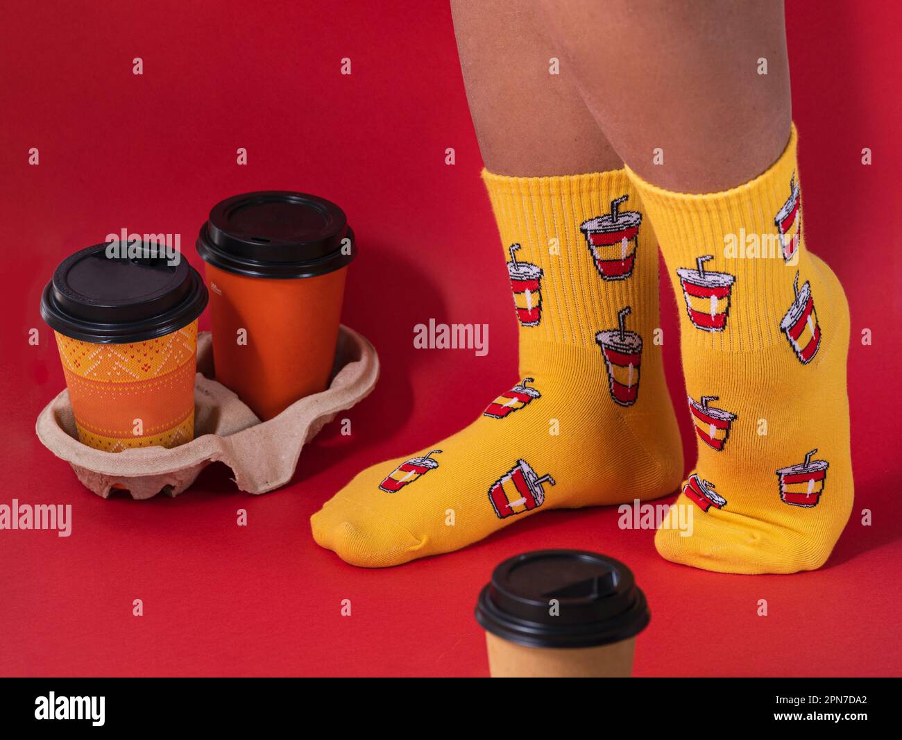 Female legs in funny socks with paper eco-friendly cups on red ...