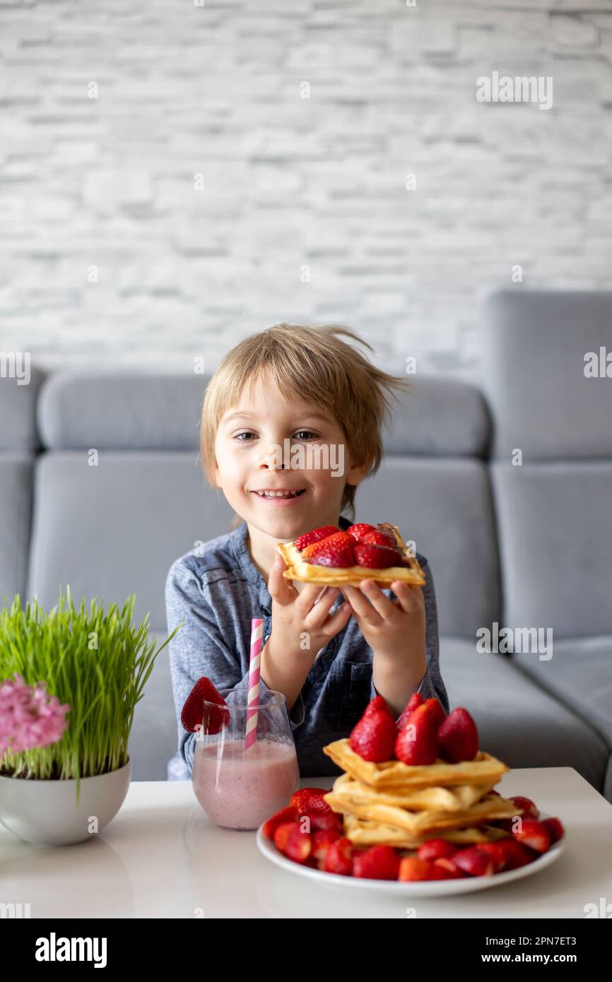 Sweet preschool child, boy, eating belgian waffle with strawberries and ...